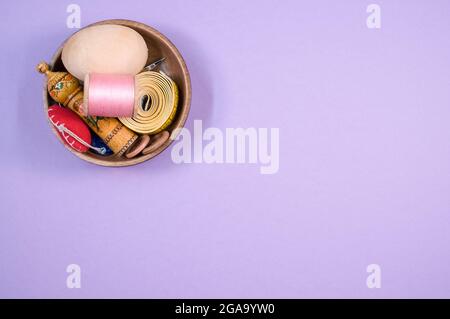 Set of sewing kit inside a wooden bowl isolated on a pink background ...