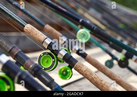 Many fishing rods on the wooden pier by the river or lake on a sunny ...