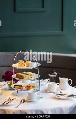 Tiered afternoon tea stand with sweet and savory treats in a cozy café ...