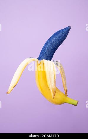 Peeled ripe banana covered with glittering paint of bright blue color ...