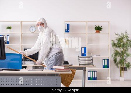 Old contractor cleaning the office holding broom Stock Photo - Alamy