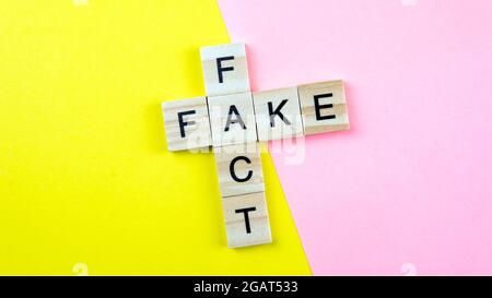 A tiles of word forming word fact and fake on a yellow and pink ...