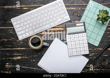 Cup of coffee, keyboard, notebooks and houseplant on light wooden ...