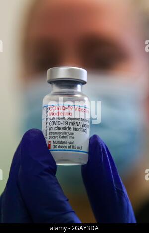A health worker holds a Moderna Covid-19 vaccine vial at a vaccination ...