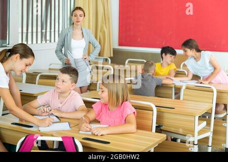 Interested preteen pupils discussing learning material in groups Stock ...