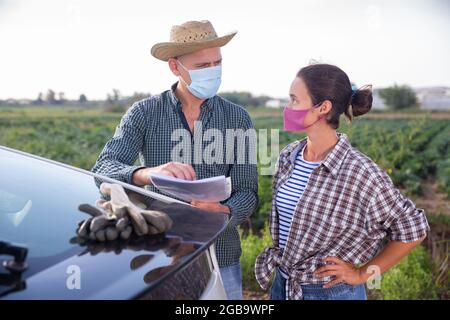 Hired worker in protective mask signs job application from farm owner ...