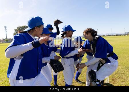 Diverse group of happy female baseball players celebrating on sunny ...