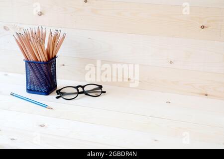 Graphite pencils in basket and eyeglasses isolated on wooden background ...