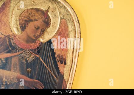 Angel ornament playing a string instrument on a yellow background with ...