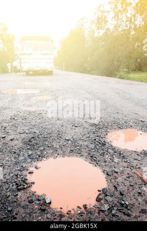 A bumpy wet gravel road after the rain, gravel road is full of potholes ...