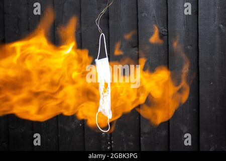 Burning single-use mask on a wooden wall background - lockdown lifted ...