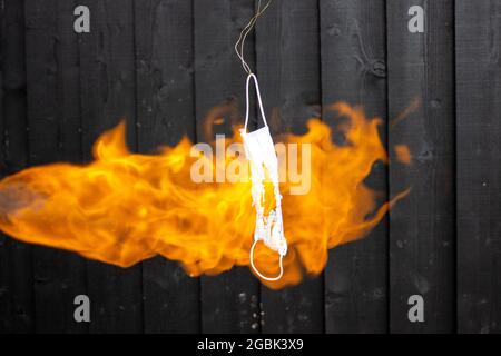 Burning single-use mask on a wooden wall background - lockdown lifted ...
