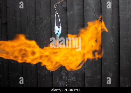 Burning single-use mask on a wooden wall background - lockdown lifted ...
