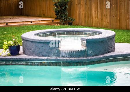 A jacuzzi hot tub next to a large freeform swimming pool with a ...