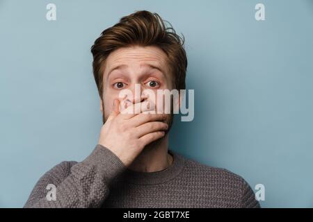 White ginger man with beard covering his mouth and looking at camera ...