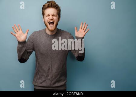 White ginger man with beard screaming while making winner gesture ...