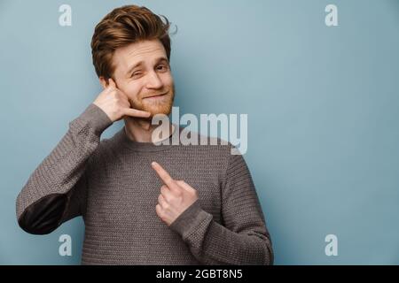 White ginger man making handset gesture and pointing finger upward ...