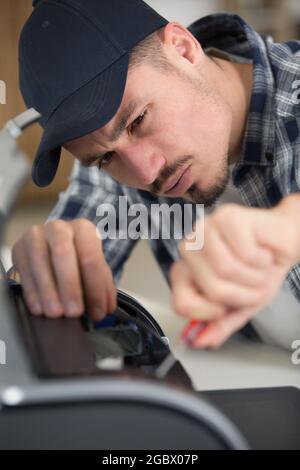 a concentrated man fixing a printer Stock Photo - Alamy