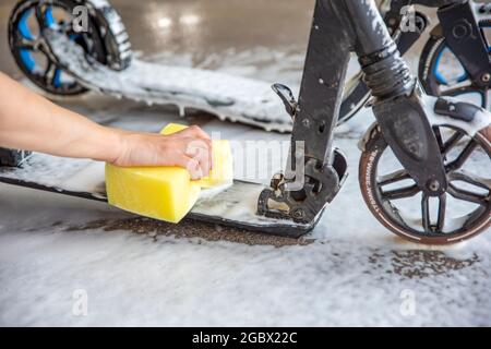 Cleaning scooter. Electric scooter care. A woman's hand washes a ...