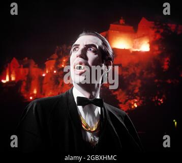 Vampire with cape showing his scary teeth over dark misty background ...