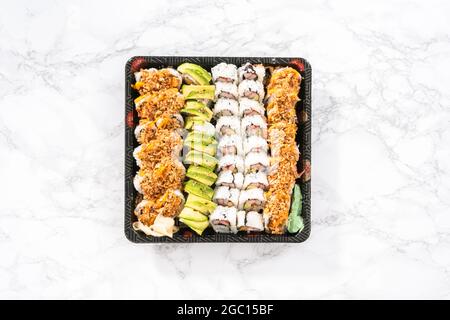 Flat lay. Pre-packaged variety of sushi and sushi rolls in a plastic ...