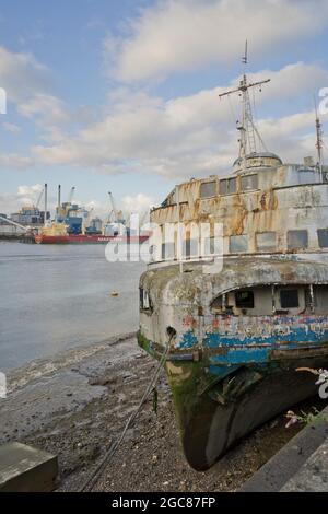 Rusty ship hull of old Mersey ferry by river Thames barrier opposite ...