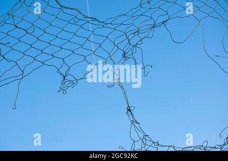 The texture of the metal mesh. Torn, destroyed, broken metal mesh on a ...