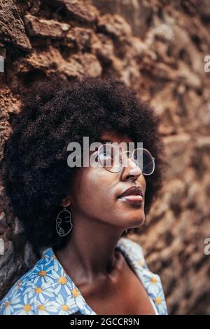afro woman with glasses and casual clothing looking at camera. She is ...