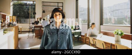 Portrait of freelancer standing in co-working space. Confident ...