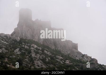 Quéribus on a foggy day. The spectacular castle sits well-defended on a ...