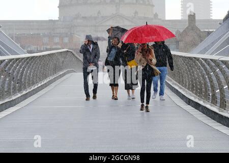London, UK. 7 August 2021. People in vintage clothing during a downpour ...