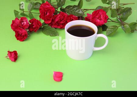Cup of coffee surrounded by red roses on the green background Stock ...
