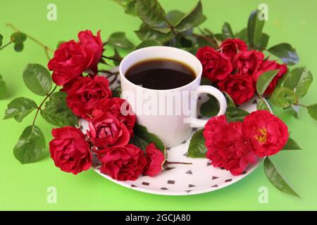 Cup of coffee surrounded by red roses on the green background Stock ...