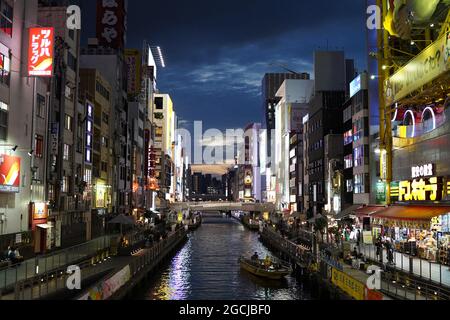 A horizontal shot of a city Osaka at night time crowded with people and ...
