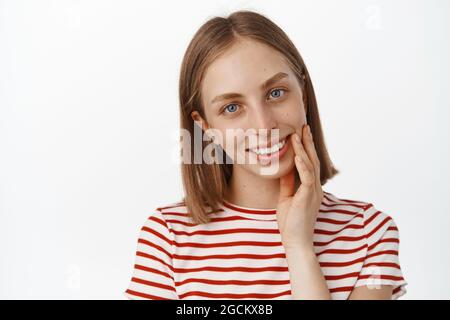 pretty girl smiling and touching her cheek with flowers and plaster on ...