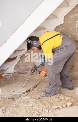 Young builder breaking up a house wall with a hammer and a chisel Stock ...