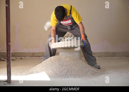 Young builder sieving sand at a construction site Stock Photo - Alamy