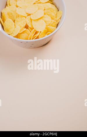Bowl of cornflakes isolated on a beige background with free space for ...