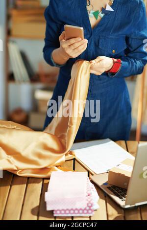 Seamstress using smartphone at work Stock Photo - Alamy