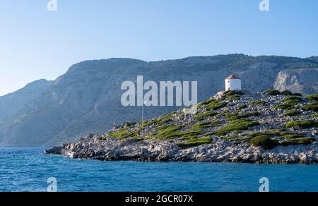 Old windmill on a rock with Greek flag, sunset, Panormitis Bay, Simi ...