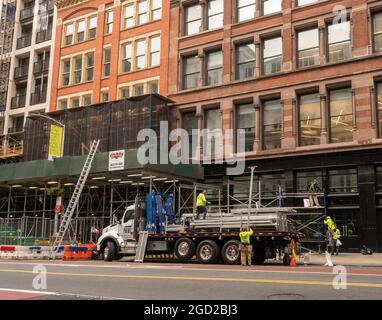 Workers construct scaffolding in the Chelsea neighborhood in New York ...