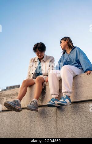 Cool and young asian couple sitting in the city posing and taking ...