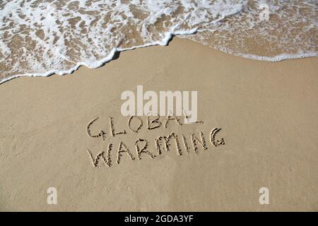 Global warming written in the sand at beach with rising wave Stock ...