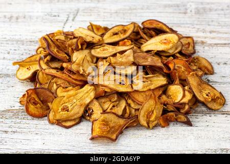A pile of dried pears in slices on a white plate on wooden background ...