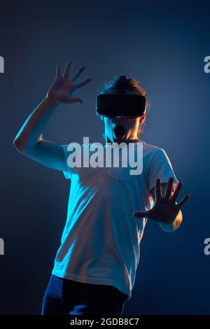 Young scared man wearing virtual reality glasses. Blurred interior ...