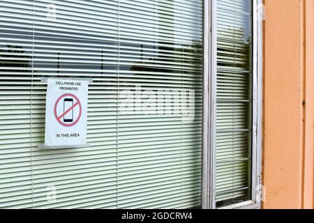 Printed sign taped on glass window warning that this is a cell phone ...