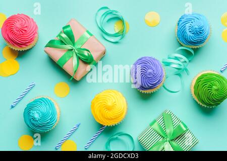Tasty Birthday cupcakes with candles and ribbons on color background ...