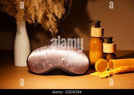 Sleeping mask with pills and cosmetic bottles on color background Stock ...