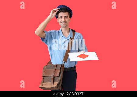 Handsome young postman with letter on color background Stock Photo - Alamy