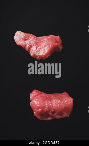 Flying raw beef meat slices and chili pepper on dark background Stock ...